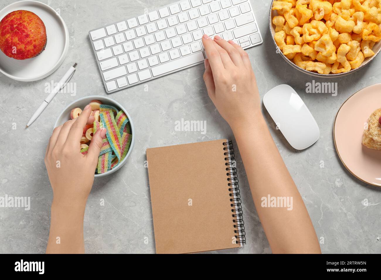 Bad habits. Woman eating different snacks while working on computer at ...