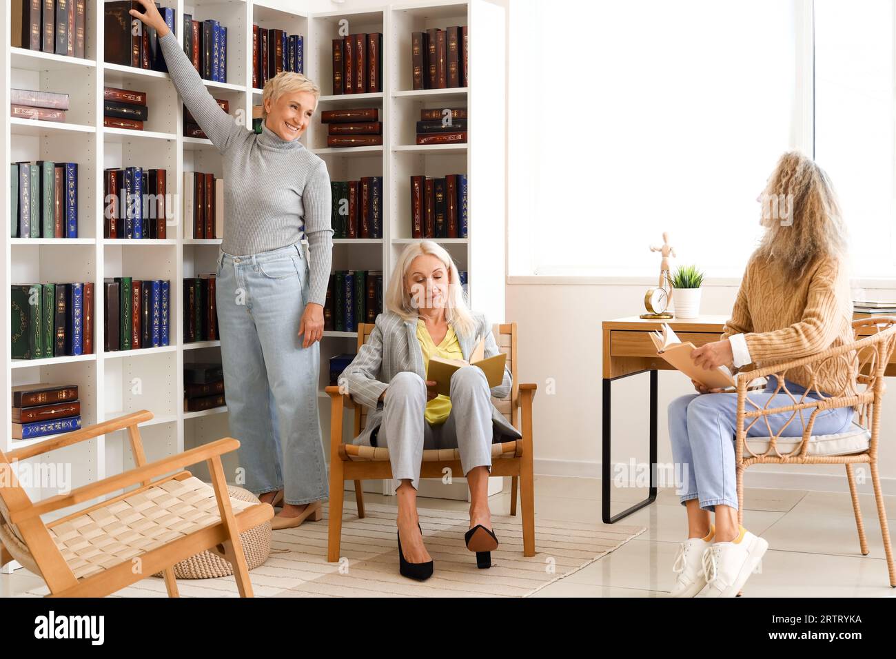 Mature women reading books at home library Stock Photo - Alamy
