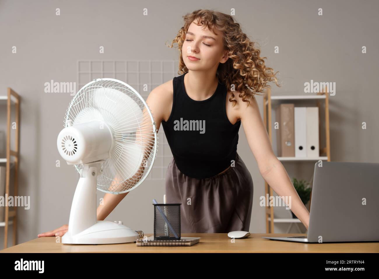 Beautiful happy young woman with electric fan at workplace Stock Photo ...