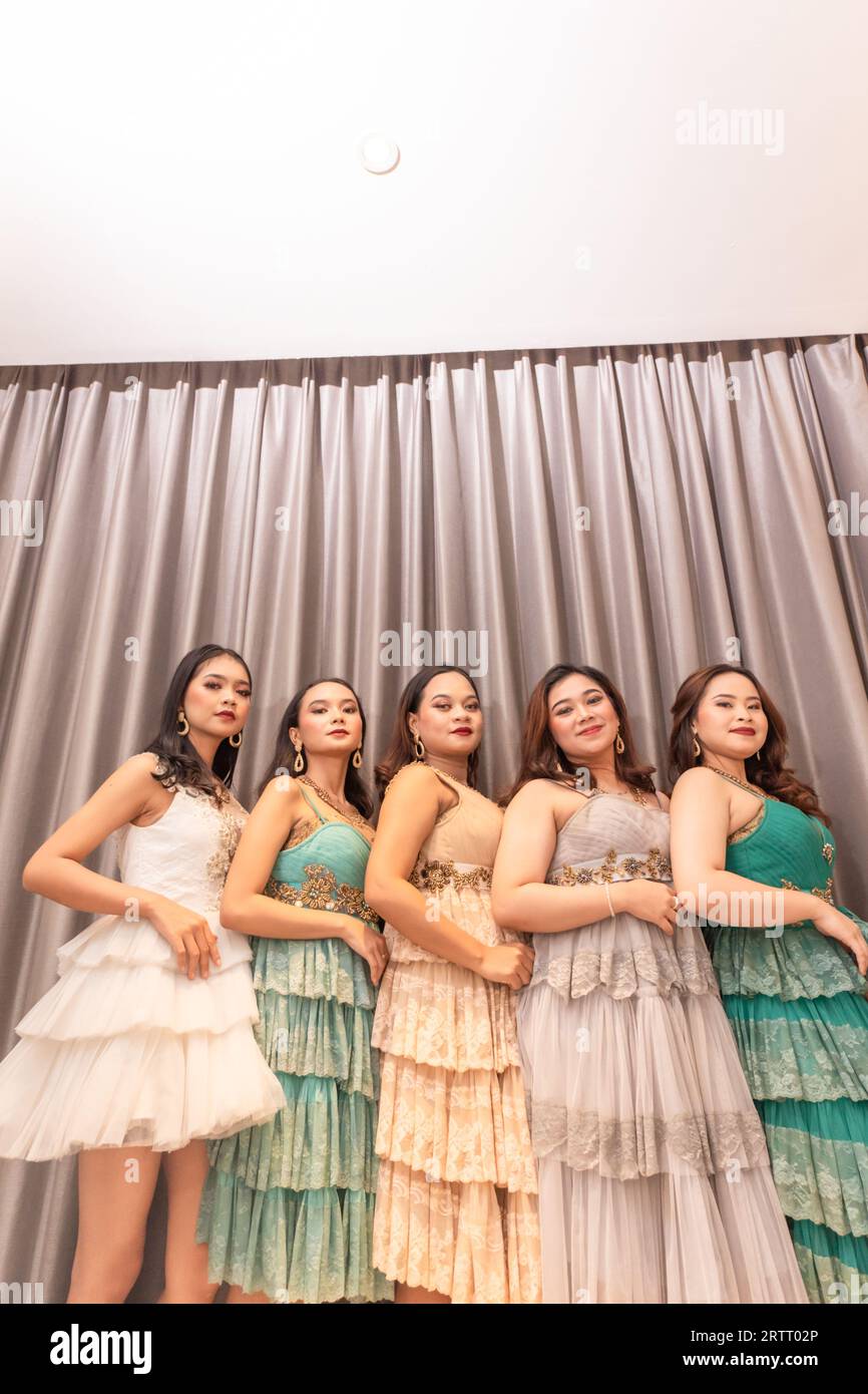 a group of Asian women are standing in front of the curtains of a ...