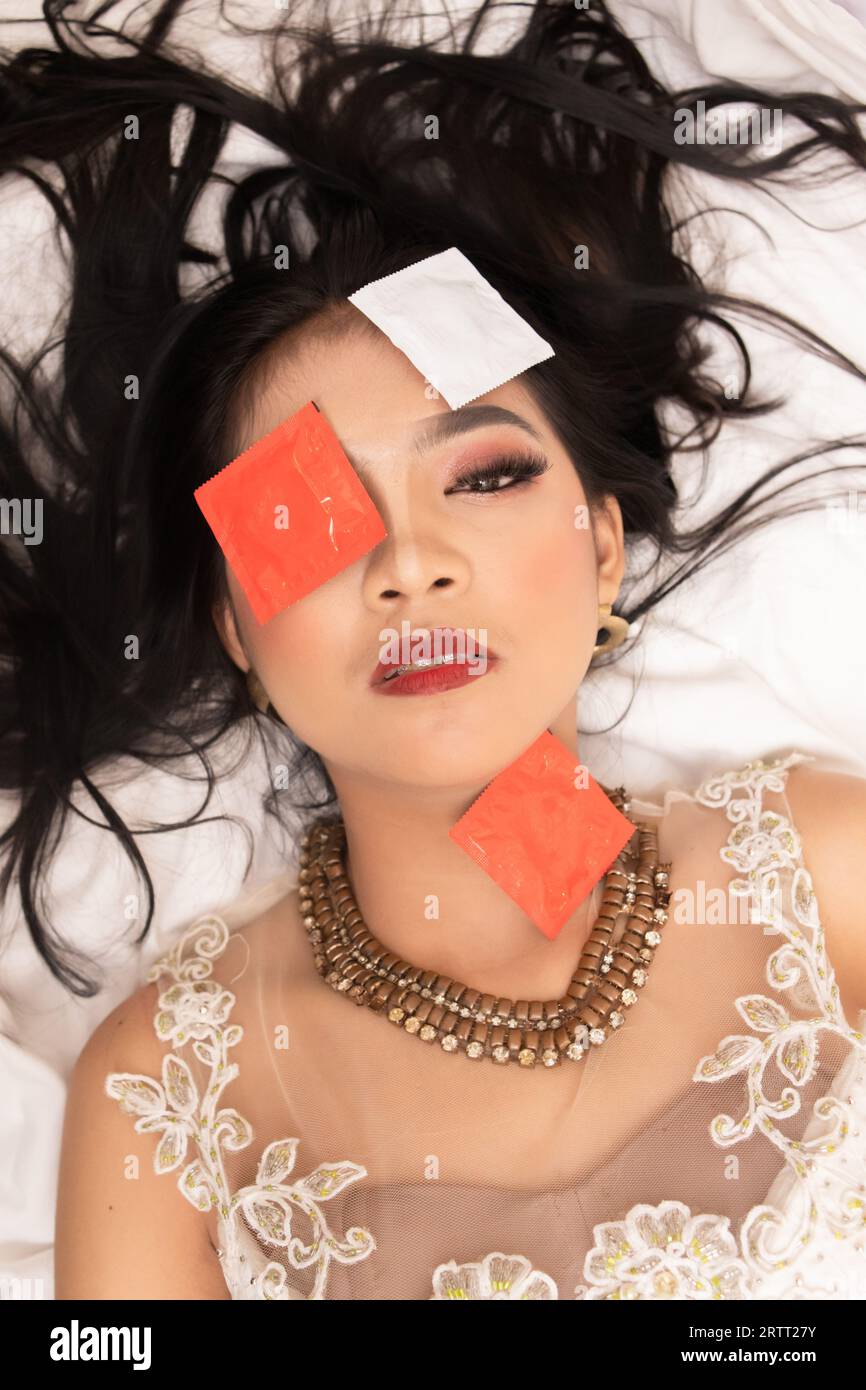 an Asian woman with a gold necklace falls asleep with a condom wrapper ...