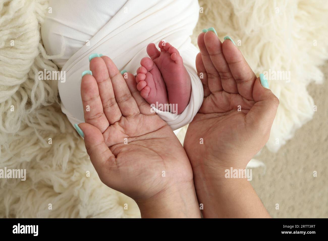 The palms of the father and mother are holding the foot of the newborn ...