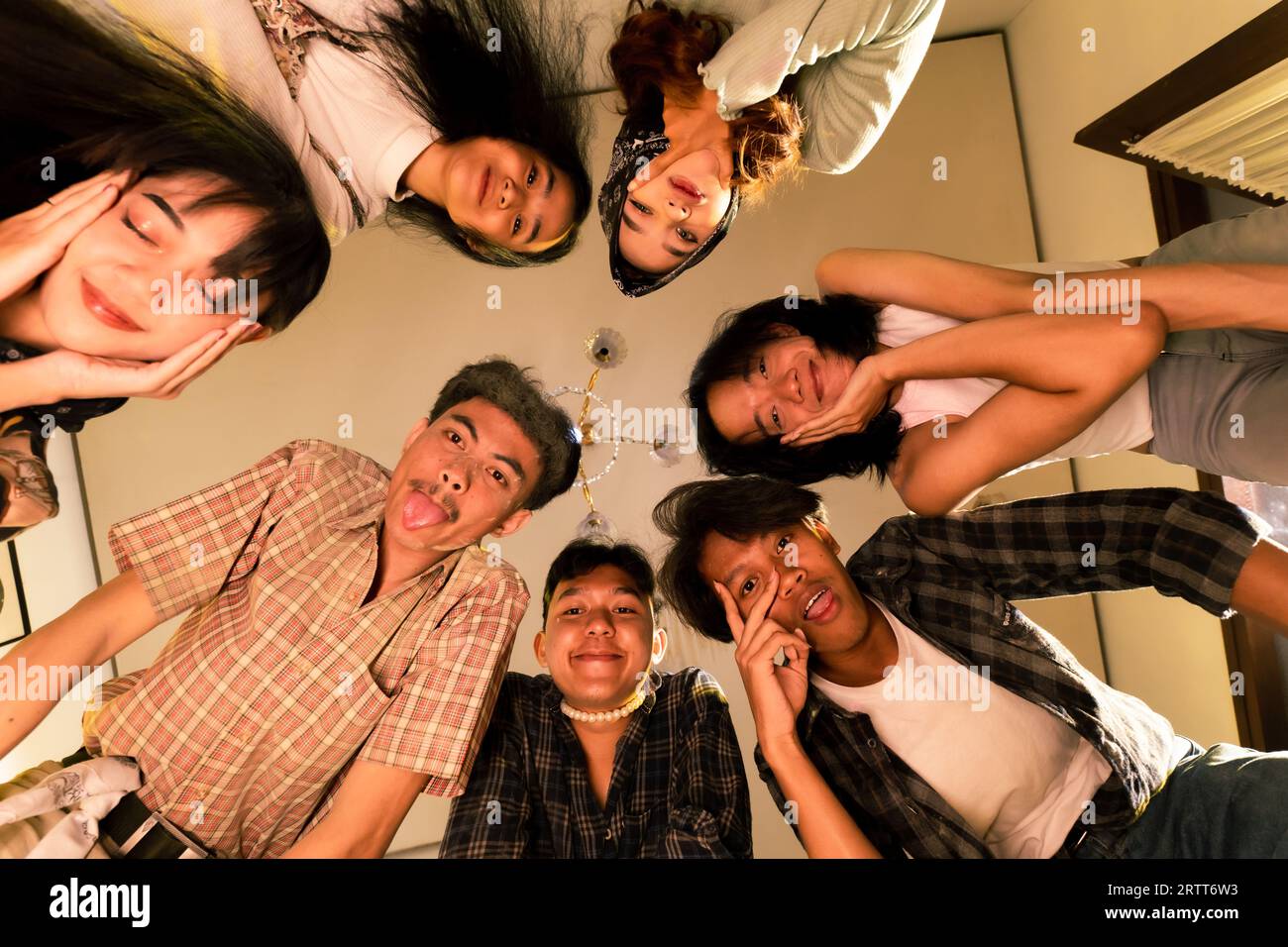 a group of Asian teenagers forming a circle and looking down with funny ...
