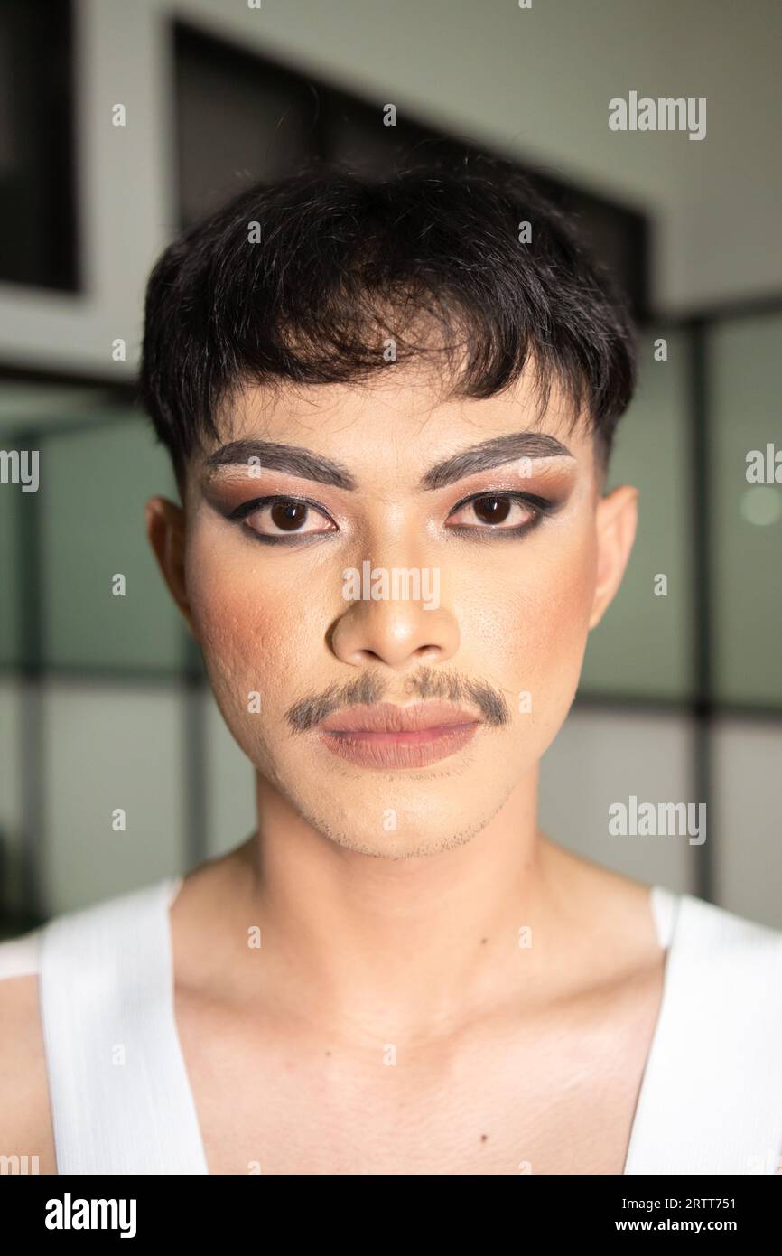 an Asian man wearing a white shirt with open sleeves and makeup on his ...