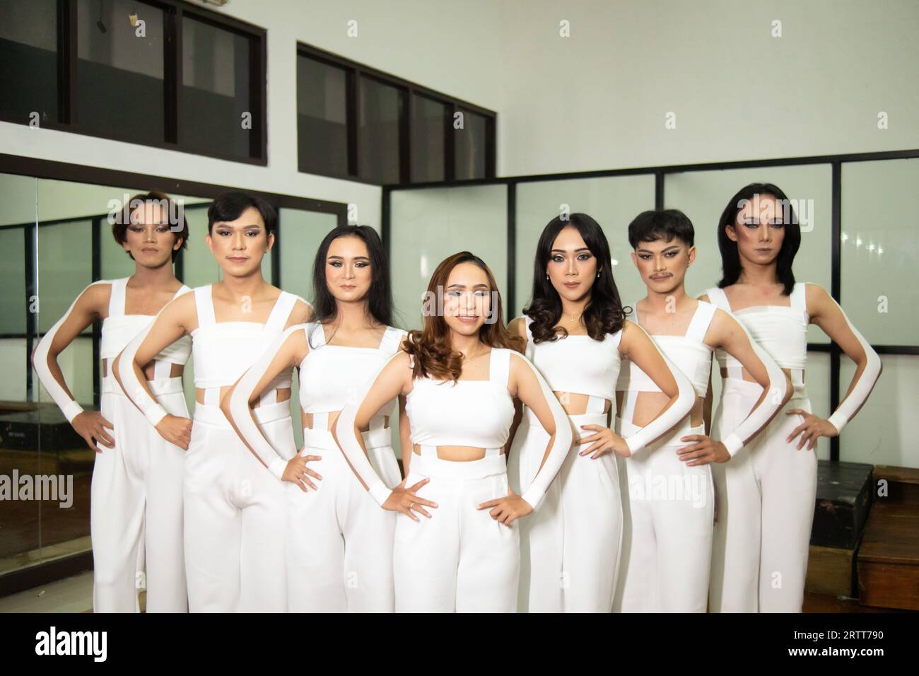 a group of Asian dancers stand side by side in white costumes in a room ...