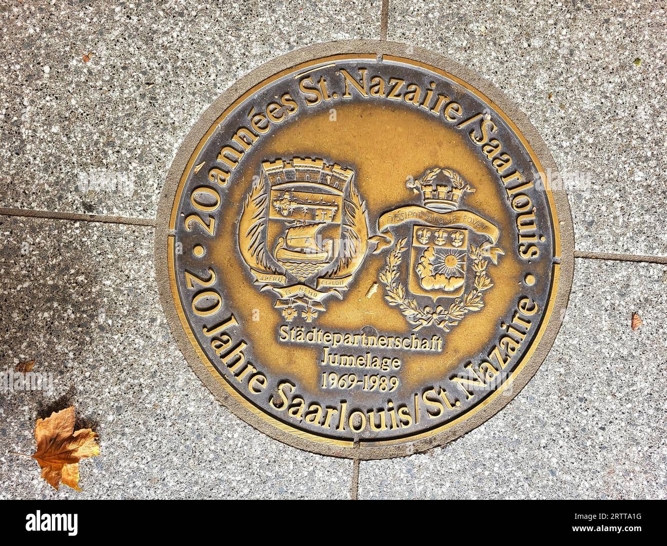 Bronze plaque embedded in a pavement. The plaque is in German and reads ...