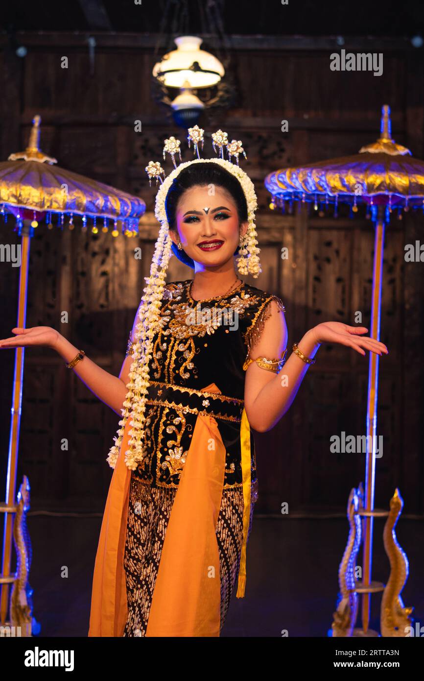 a Javanese dancer in jasmine and a yellow shawl takes selfies on stage ...