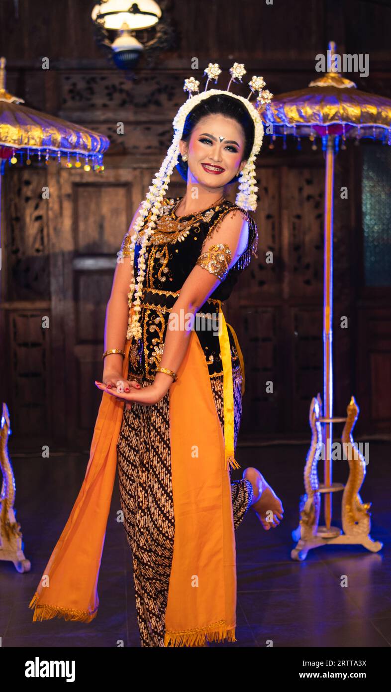 a Javanese dancer in jasmine and a yellow shawl takes selfies on stage ...