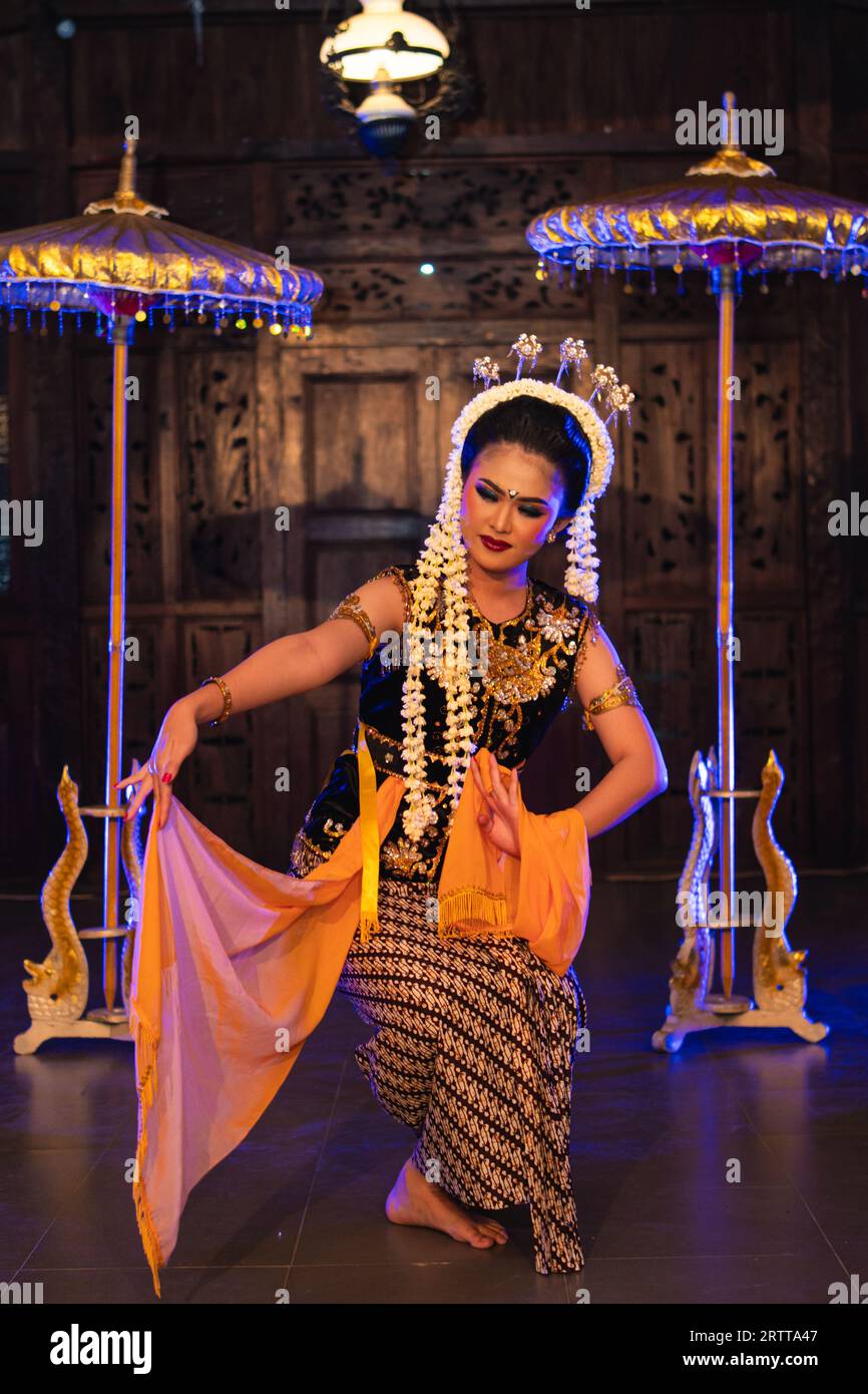 a Javanese dancer in jasmine and a yellow shawl takes selfies on stage ...