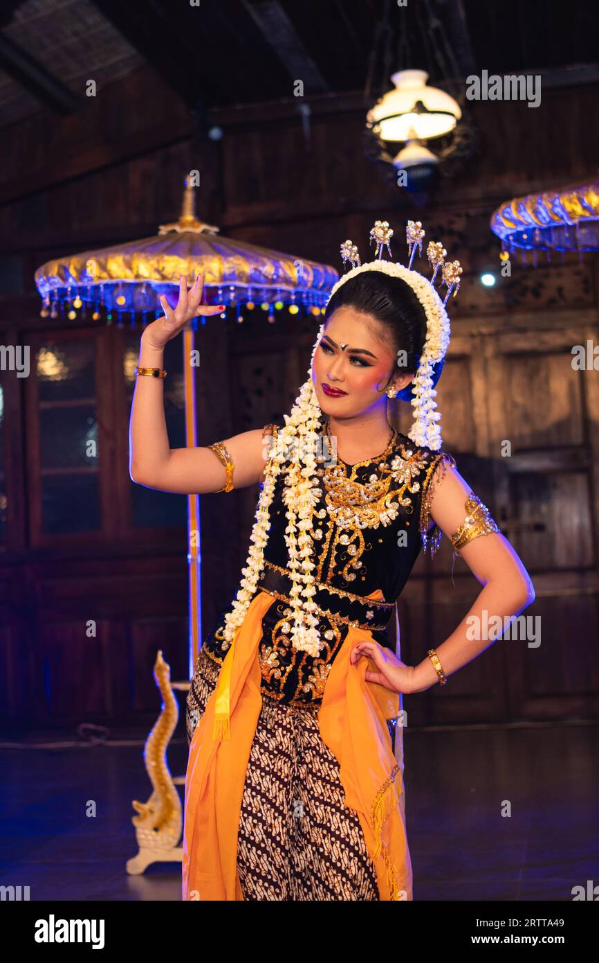 a Javanese dancer in jasmine and a yellow shawl takes selfies on stage ...