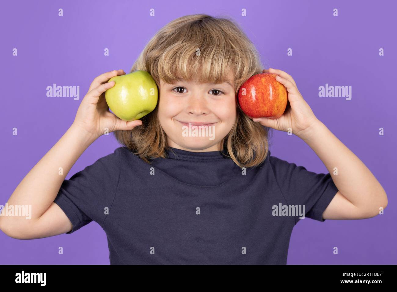 Funny kid boy hold a red apple and a green apple. Isolated on studio ...
