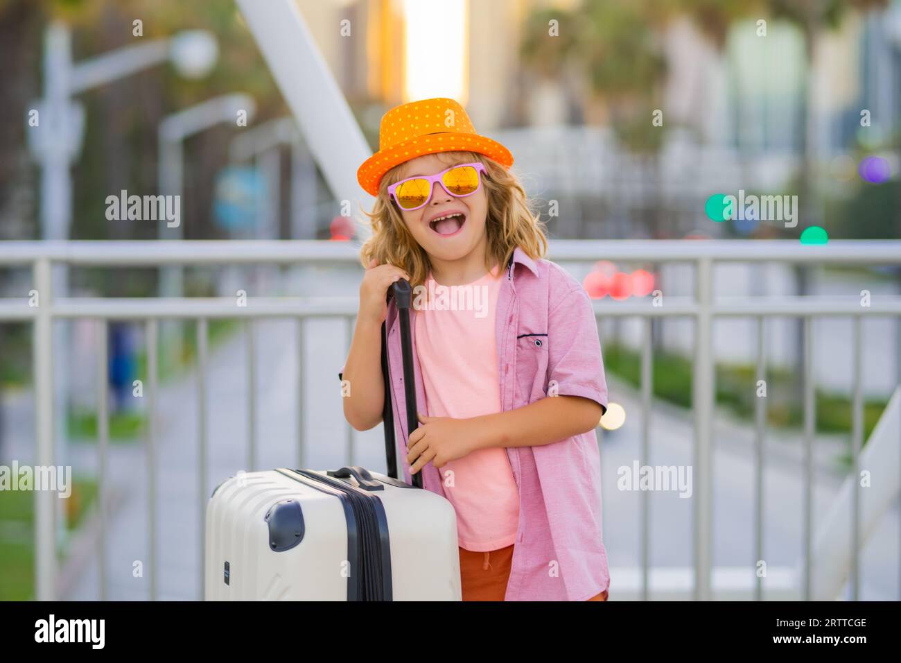Kids travel. Happy child boy carrying suitcases outdoor on city street ...