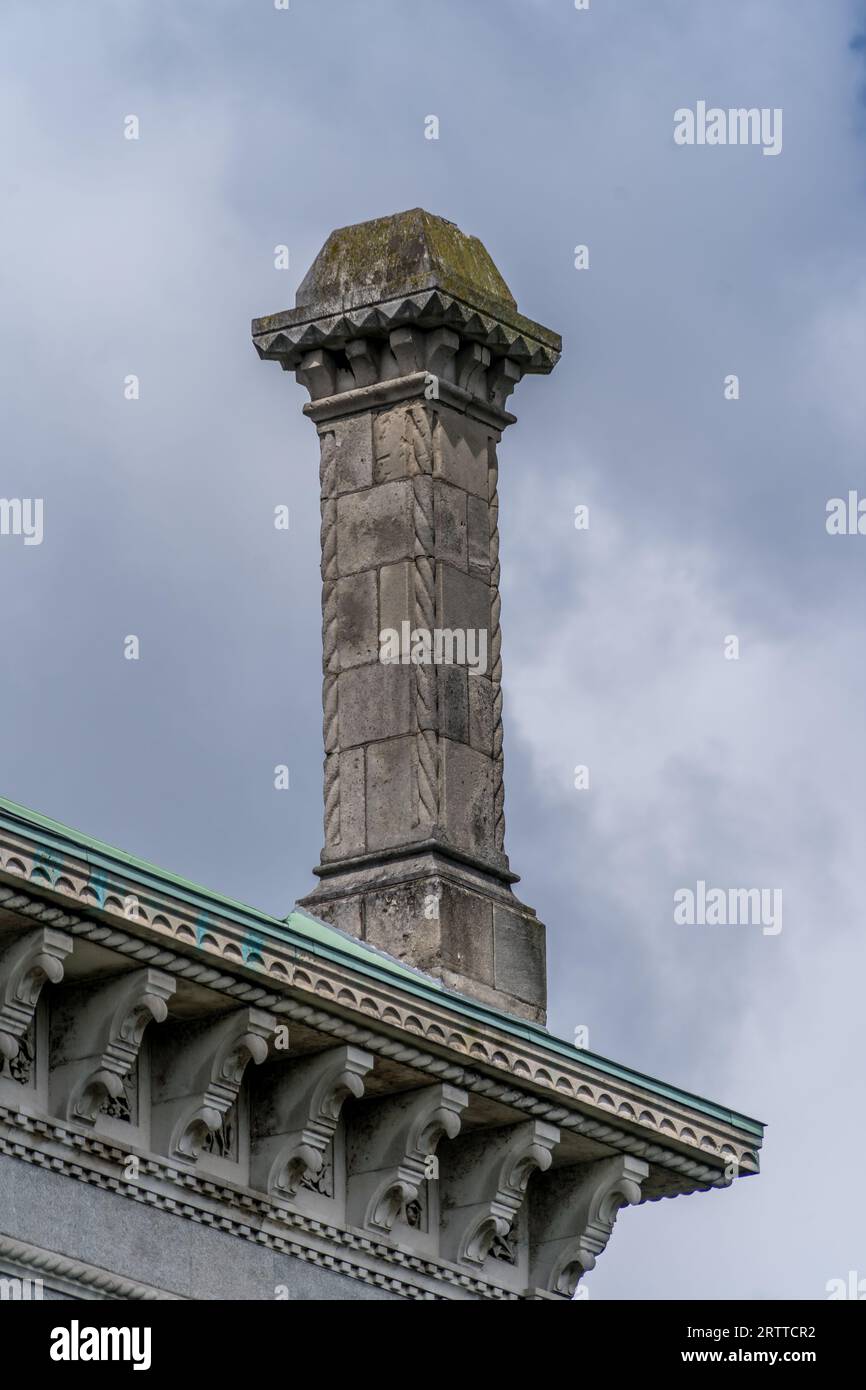 Close up view of tall traditional classic stone chimney on a rooftop ...
