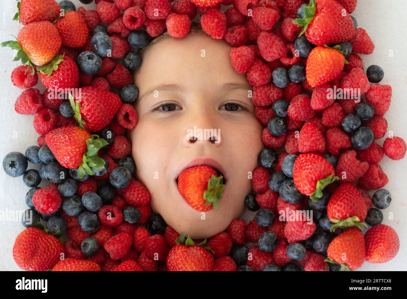 Healthy vitamins fruits. Child face with berry frame, close up. Berries ...