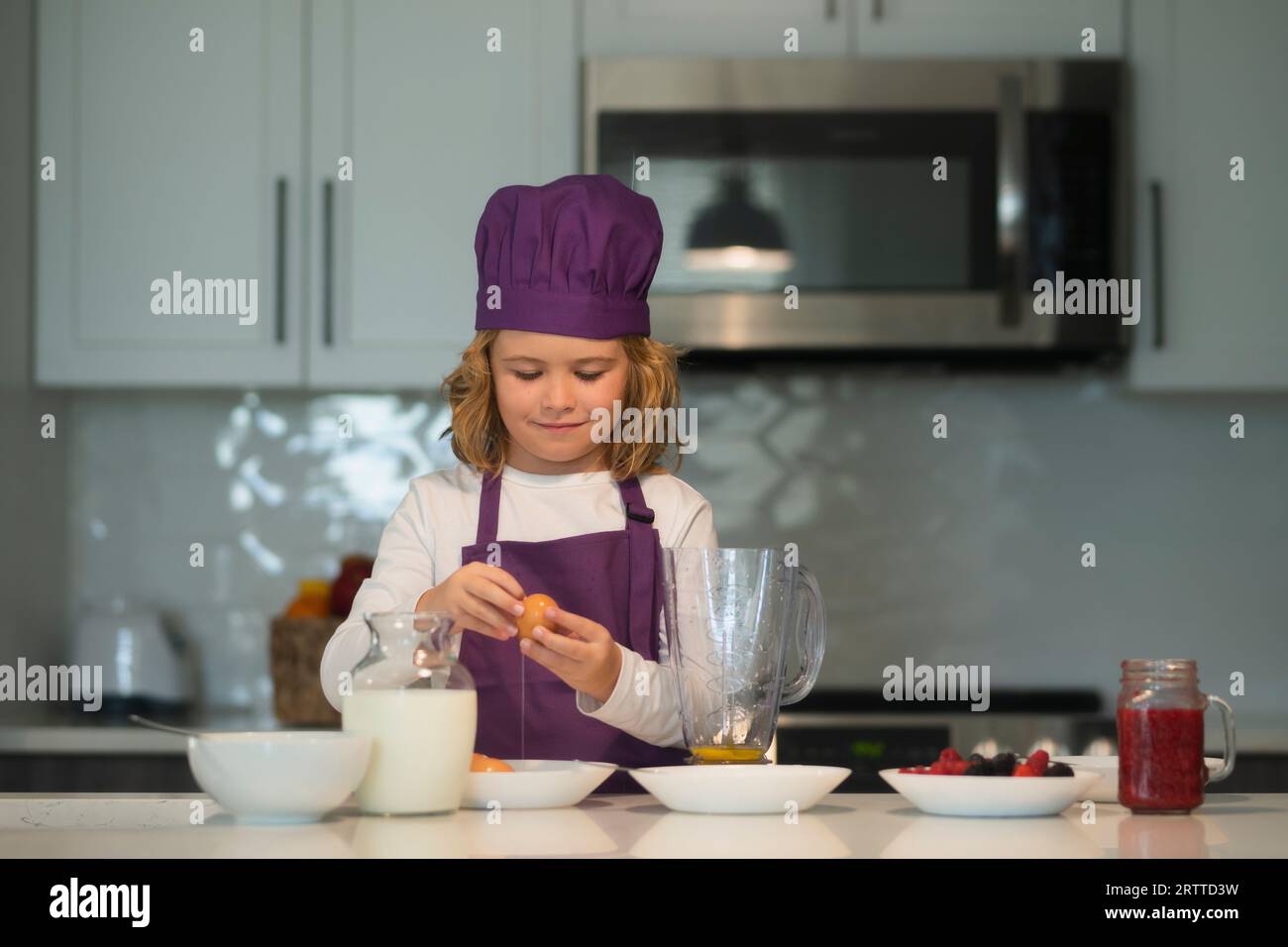 Cooking in kitchen. Little kid boy in chef hat and an apron cooking in ...