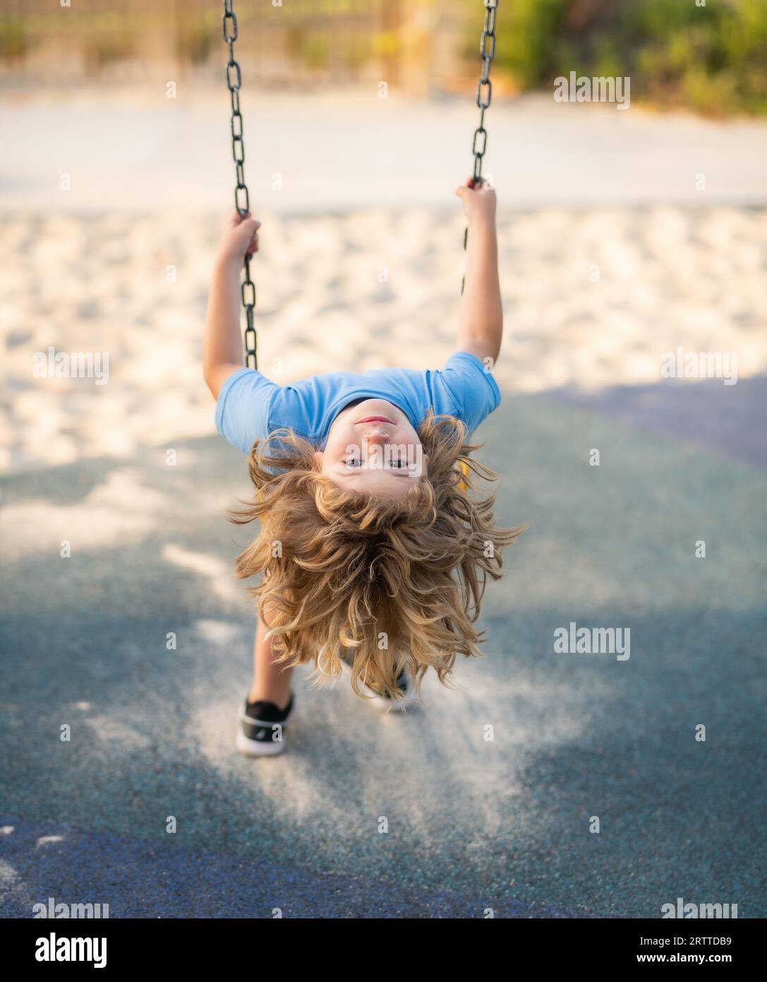 Swinging on playground. Funny kid on swing. Little boy swinging on playground. Happy cute ...