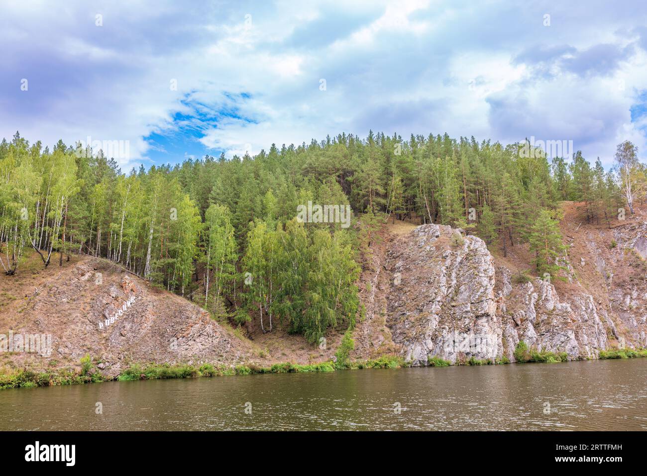Pine trees and rocks on the river shore with fall foliage around. Rocky ...