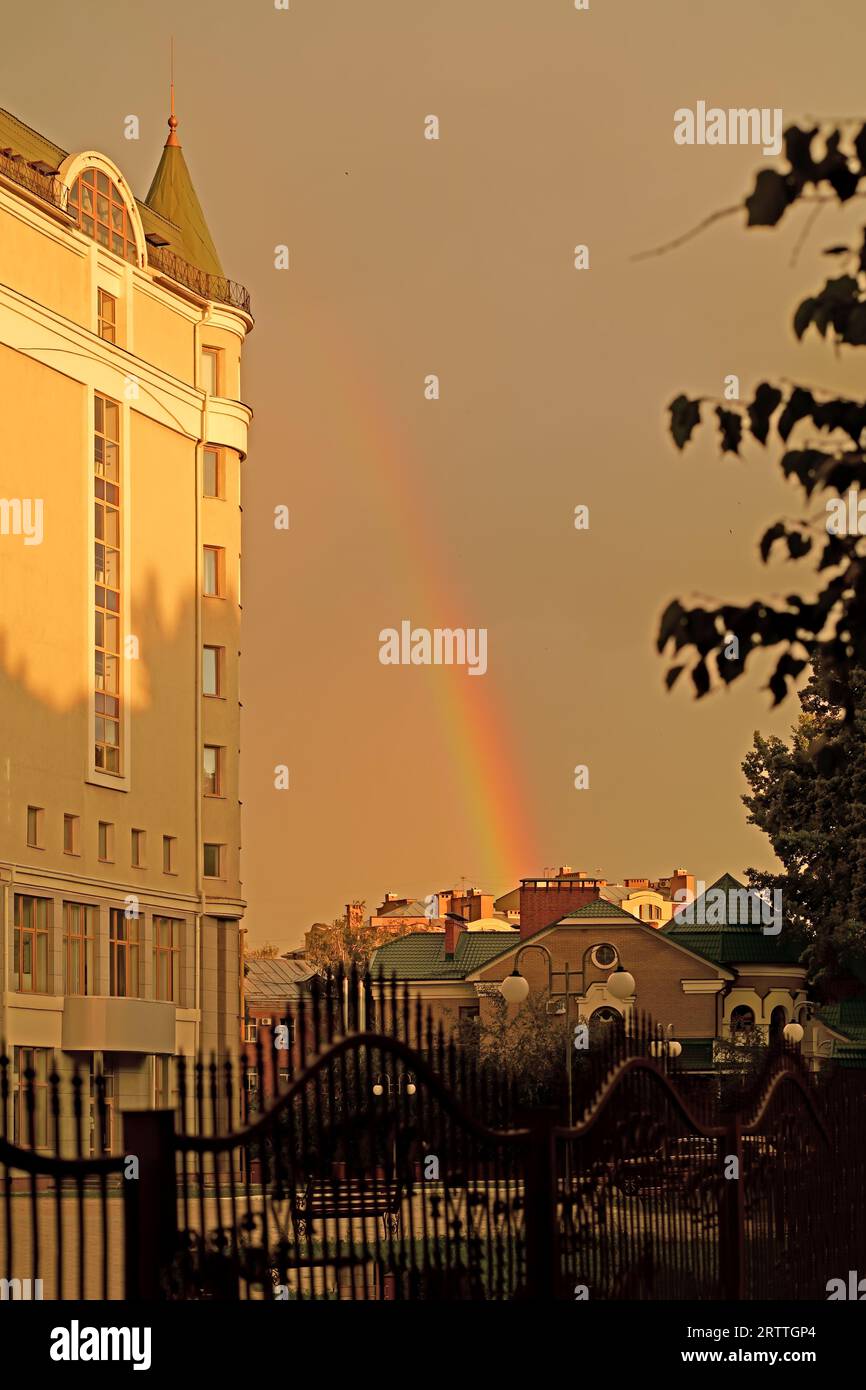 It's raining and rainbows in the city. City buildings, rooftops and ...