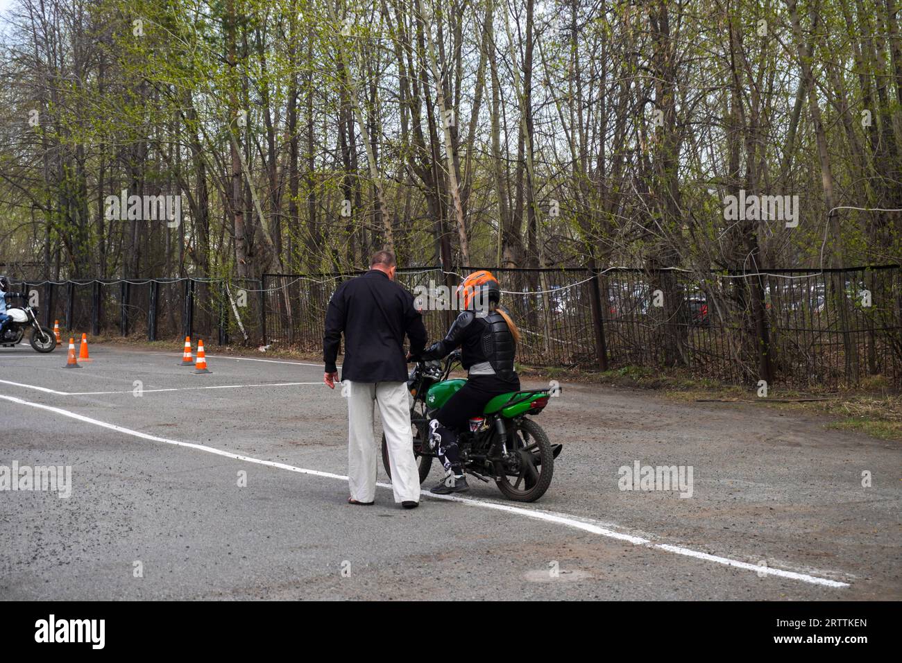 A young woman is learning to ride a motorbike in a motorcycle school ...