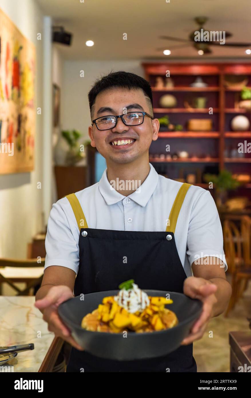 Vietnamese man chef in uniform holding fresh baked belgian waffles with ...