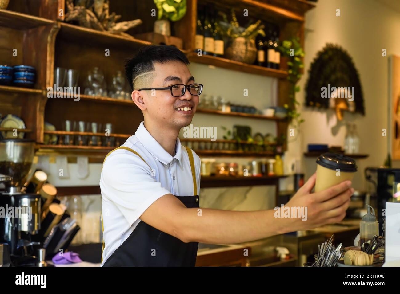 Vietnamese smiling waiter holding paper cups with coffee in a cafe ...