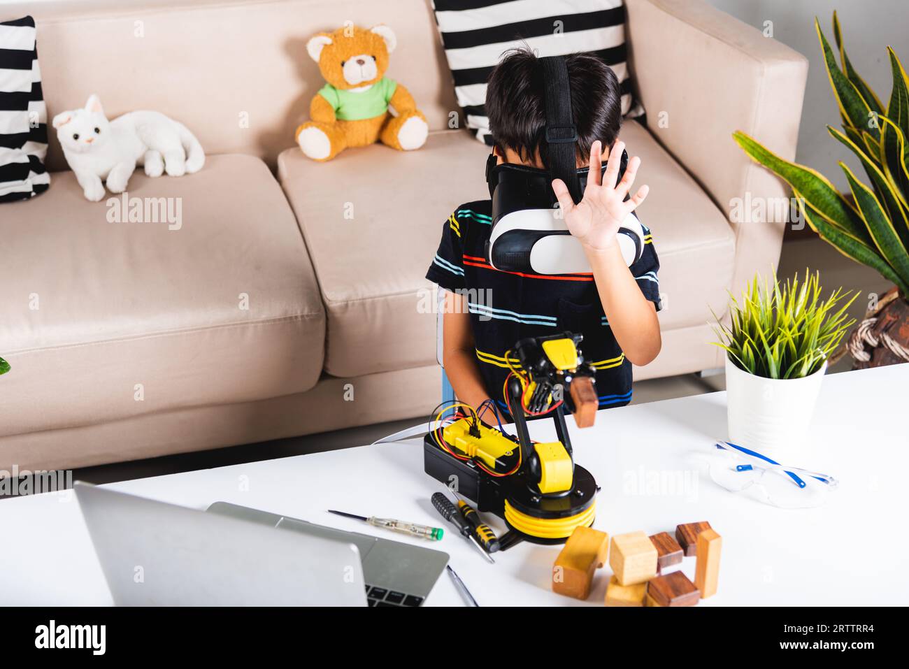 Asian kid boy using VR glasses on robotic arm in workshop Stock Photo ...
