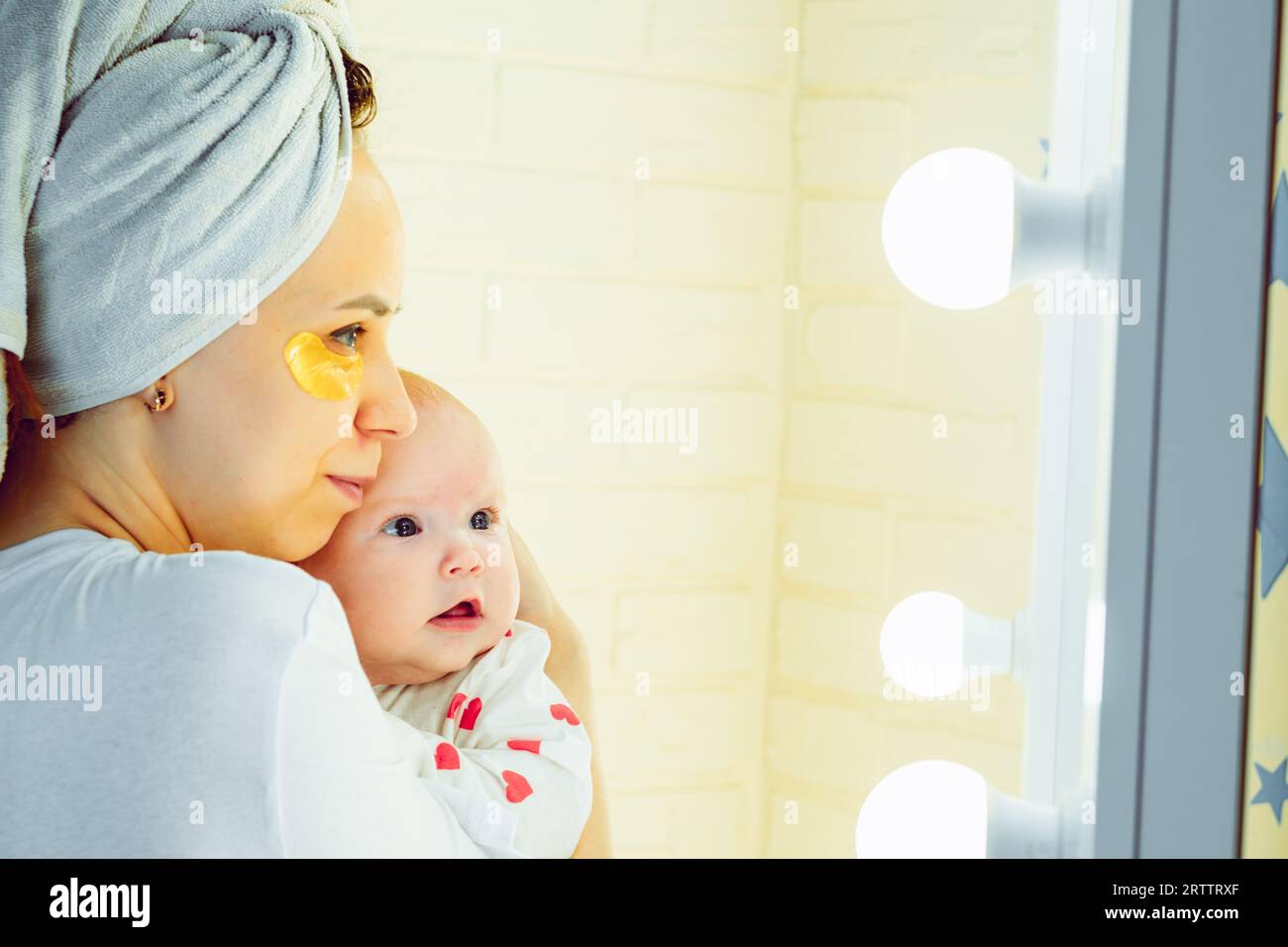 Young mother take care of her skin with under eye patches holding her ...