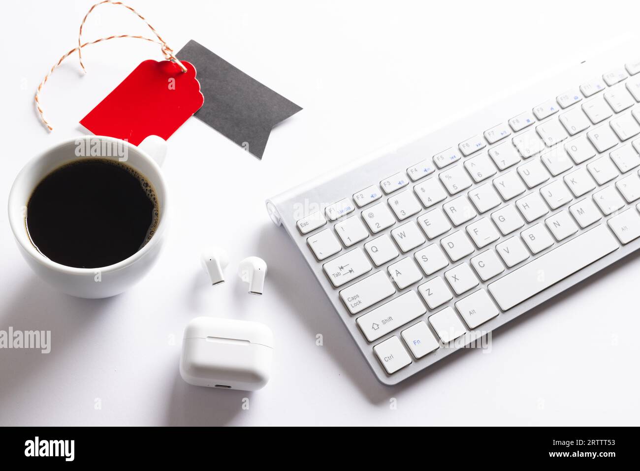 Computer keyboard, cup of coffee, wireless earphones, gift tags with ...