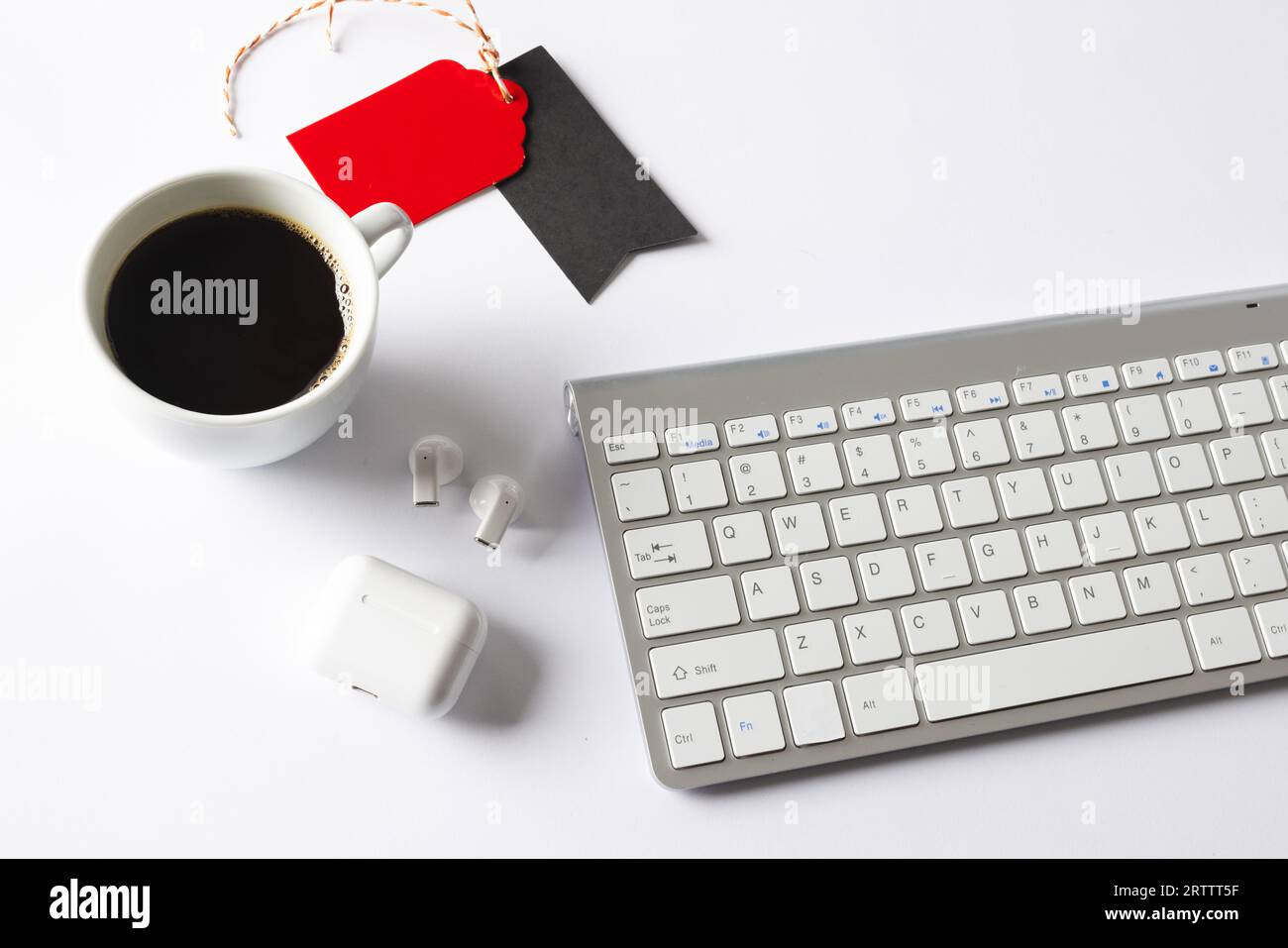 Computer keyboard, cup of coffee, wireless earphones, gift tags with ...