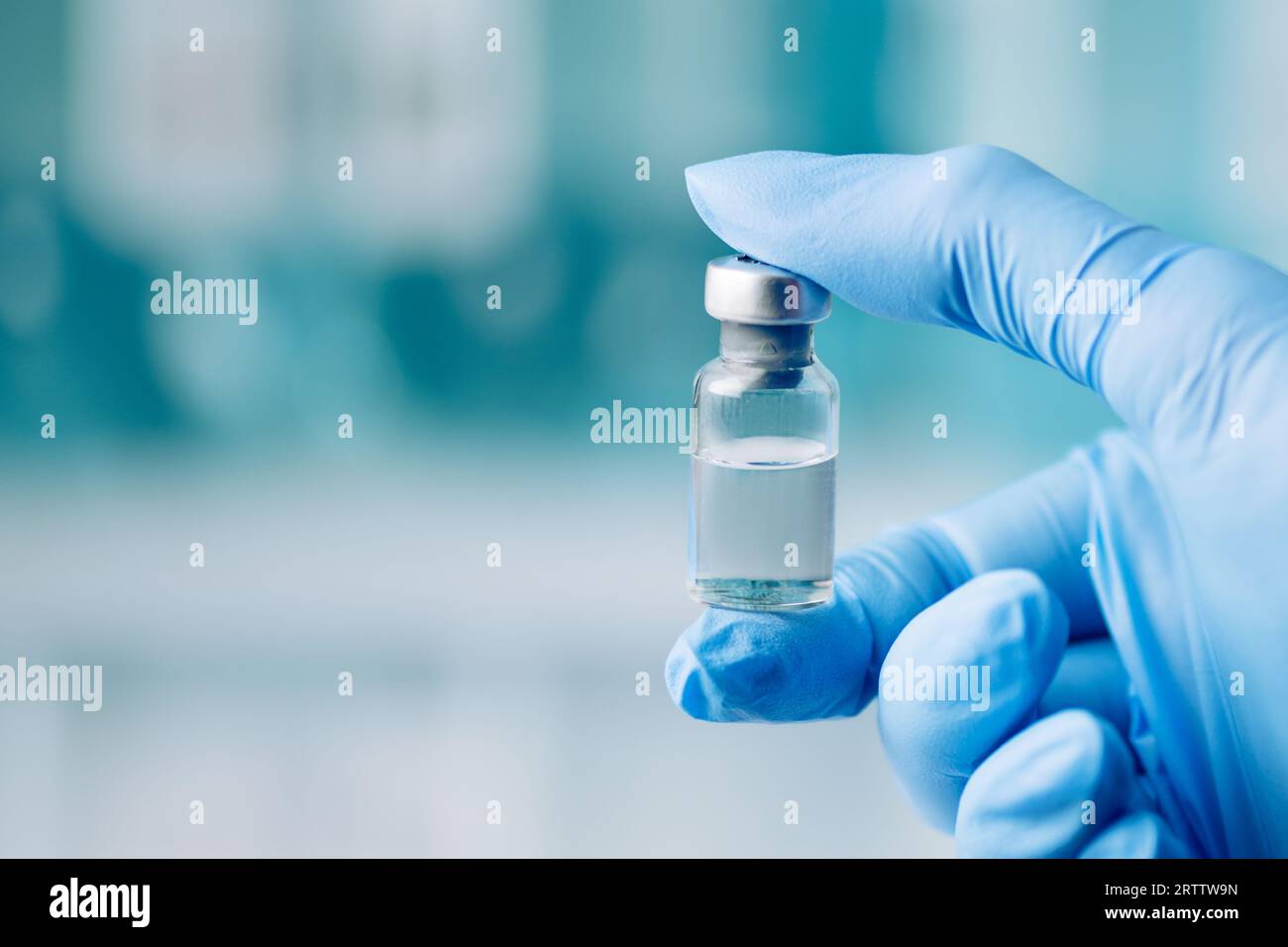 Doctor's hand holding glass vial with injection over blue background ...