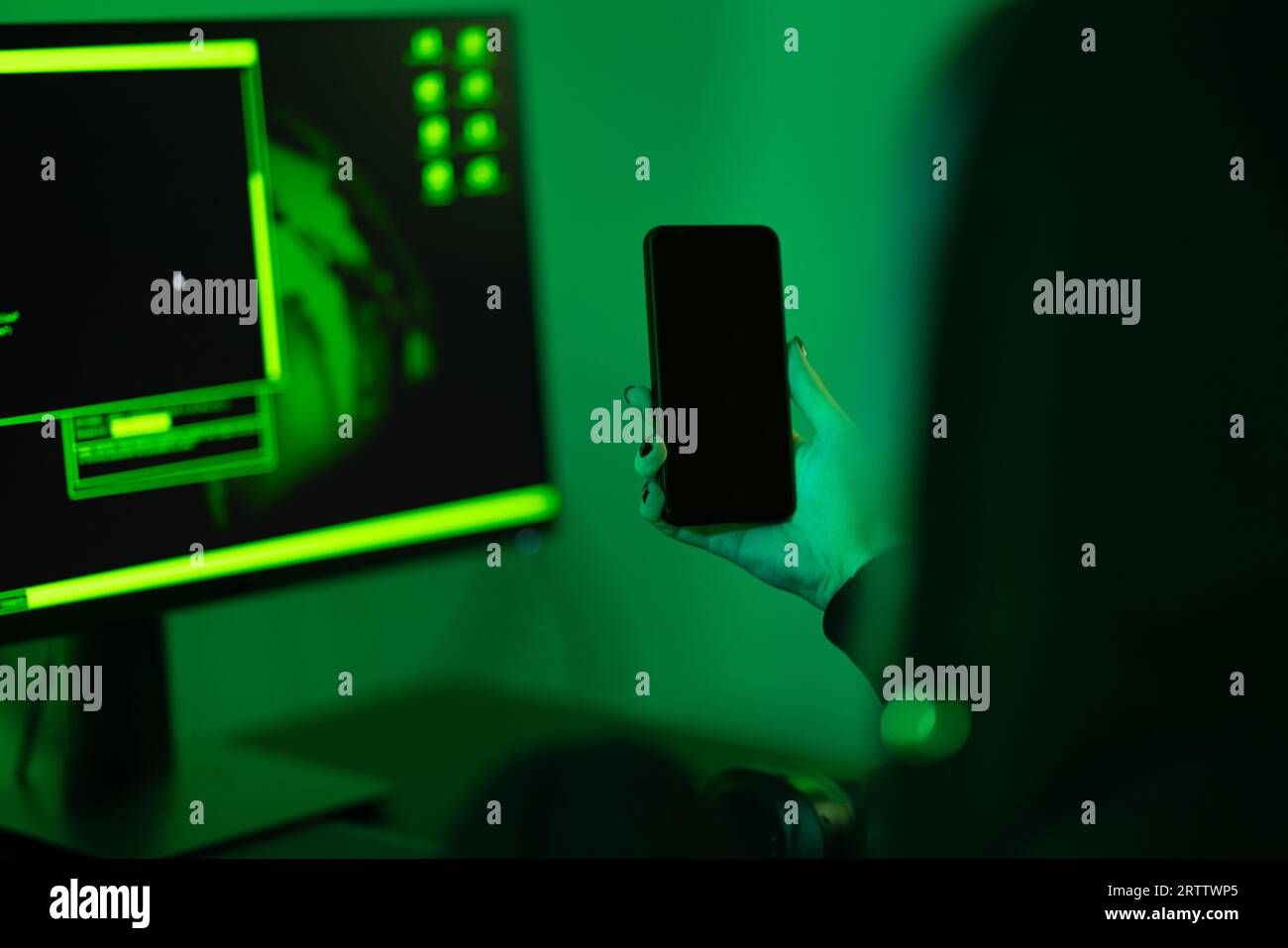 Cyber security concept showing hacker holding mobile phone in dark room ...