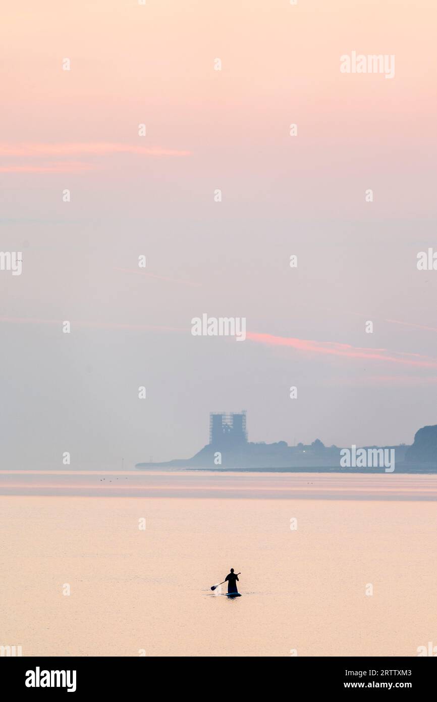 Man paddling on a paddle board along a flat calm sea at Herne Bay on a ...