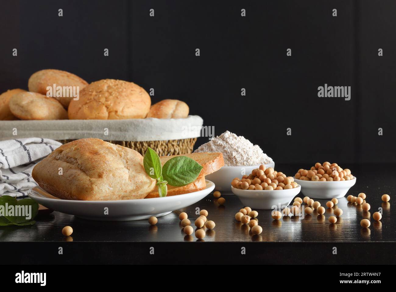 Bread rolls with soy flour on black kitchen bench with bowls full of ...