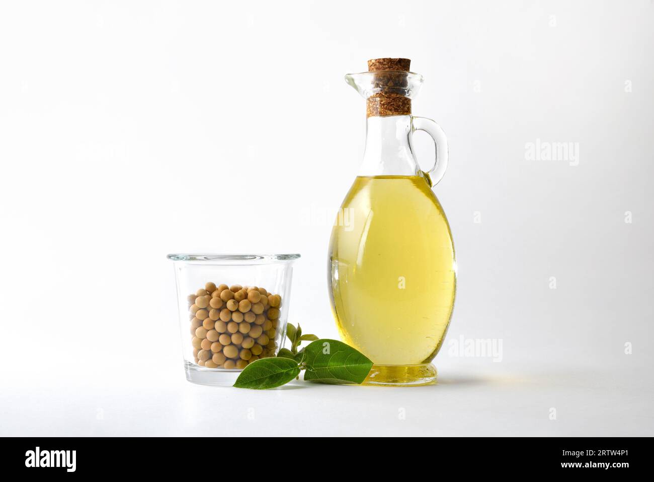 Soybean oil and dry soy beans in glass container and leaves white ...