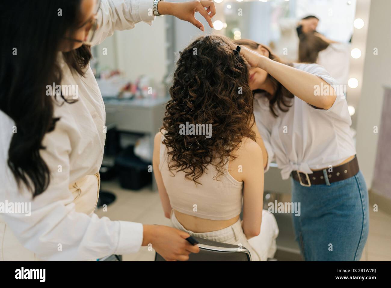 Back view of makeup artist preparing to apply makeup to young woman ...