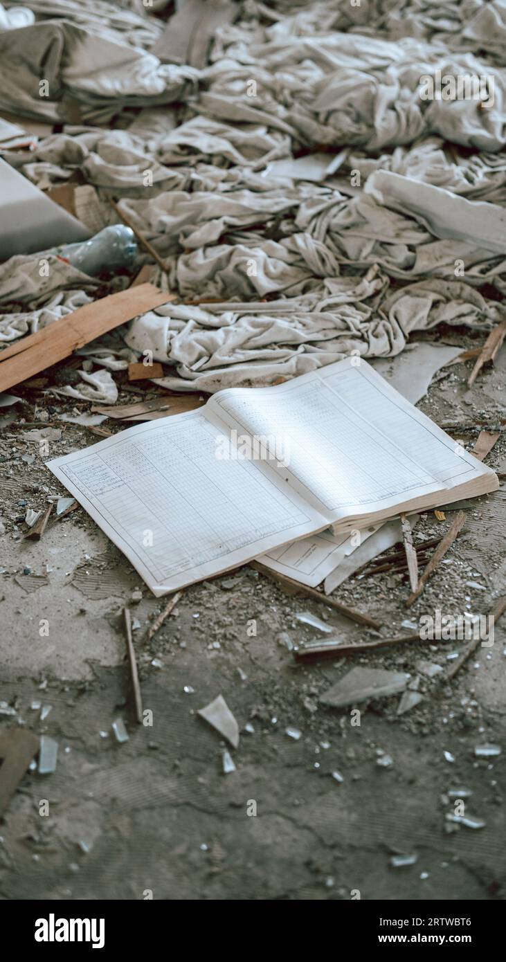 A vintage book lying amidst a pile of discarded items including clothes ...