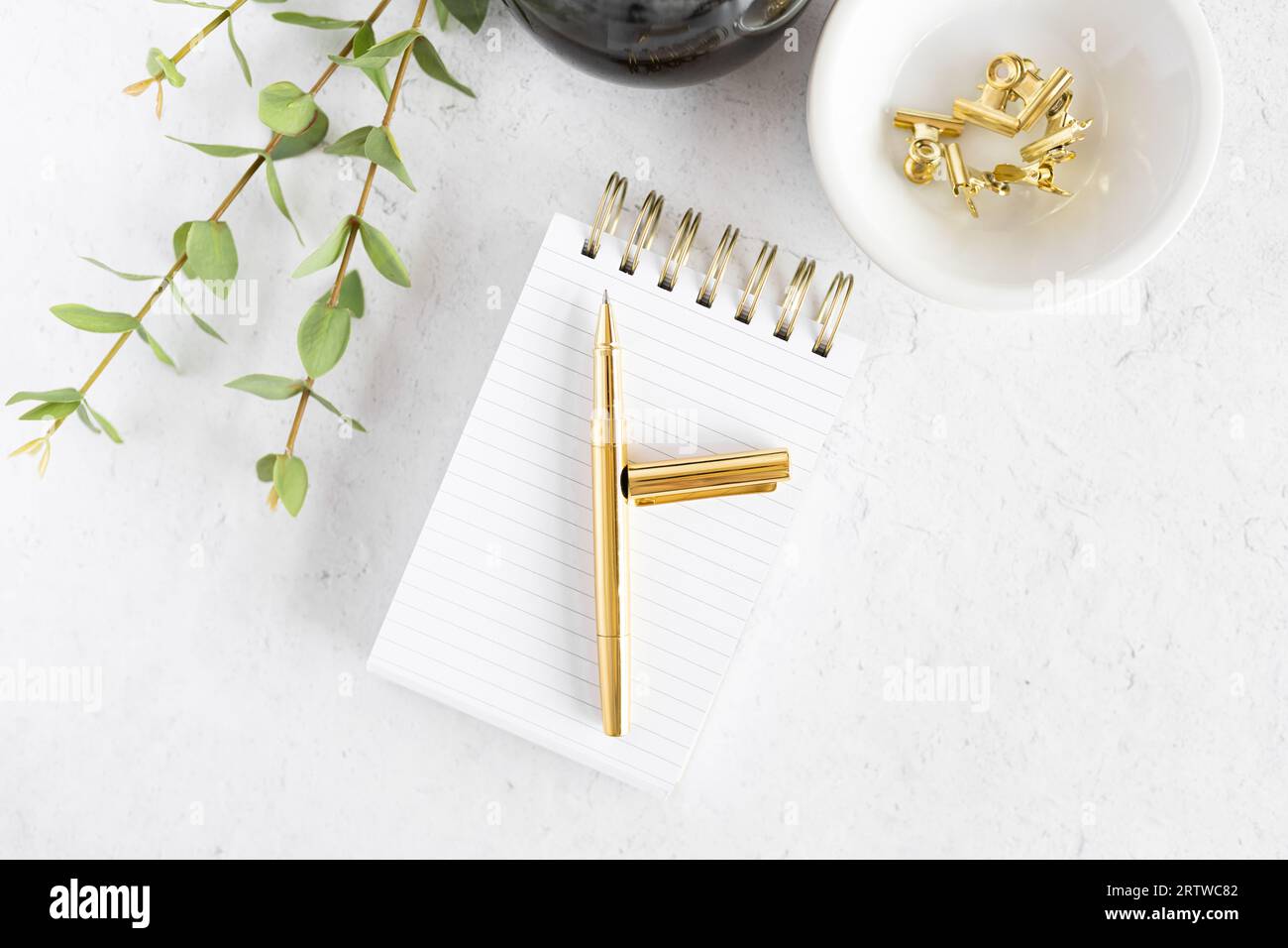 A notepad with a gold pen and office supplies Stock Photo - Alamy