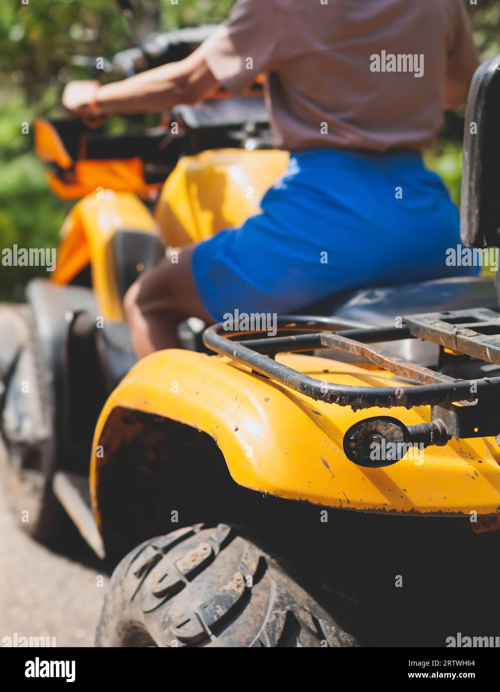 Group of riders riding ATV vehicle crossing forest rural road, process ...