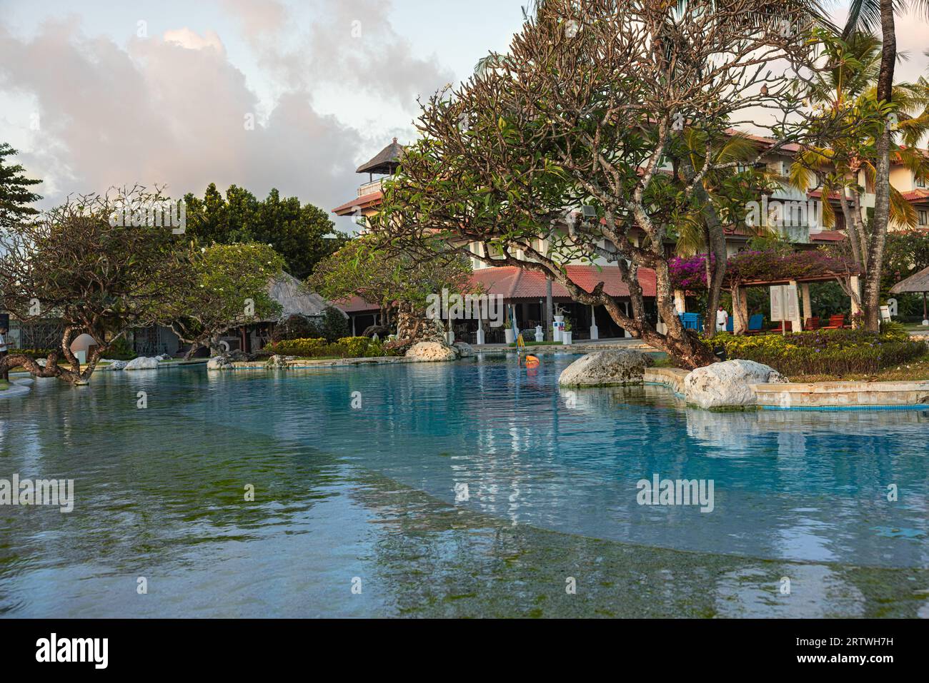 A crystal clear swimming pool with a serene stone border in Bali ...