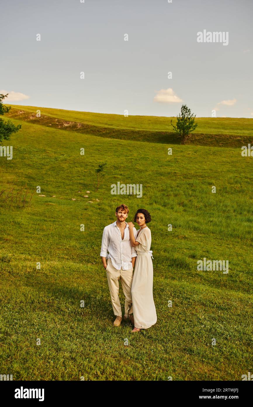 just married multicultural couple standing together in green field ...