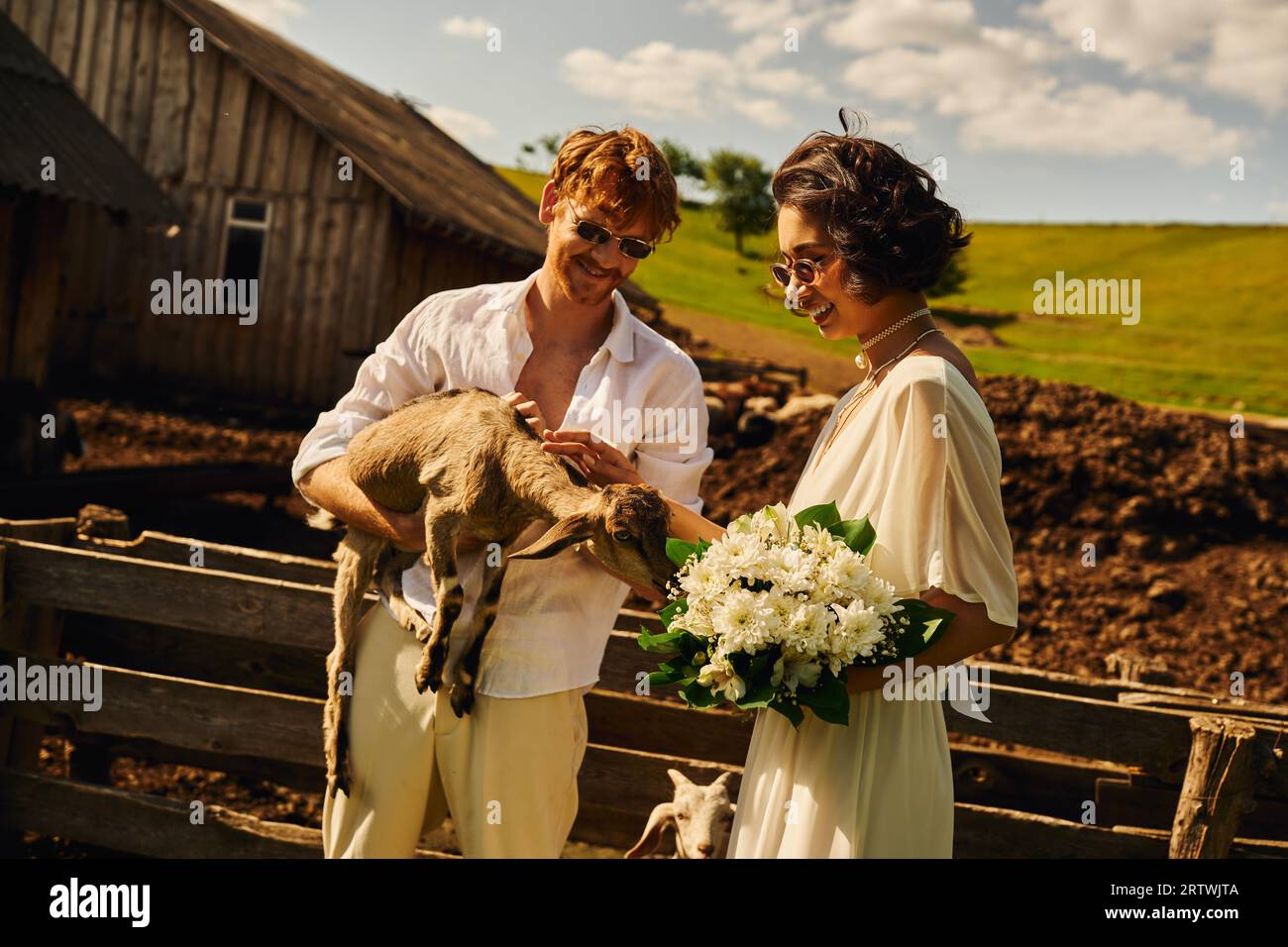 happy multiethnic newlyweds cuddling cute baby goat, asian woman in ...