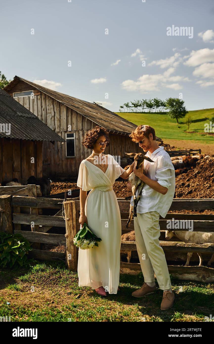 happy multiethnic couple in wedding gown and sunglasses cuddling cute ...