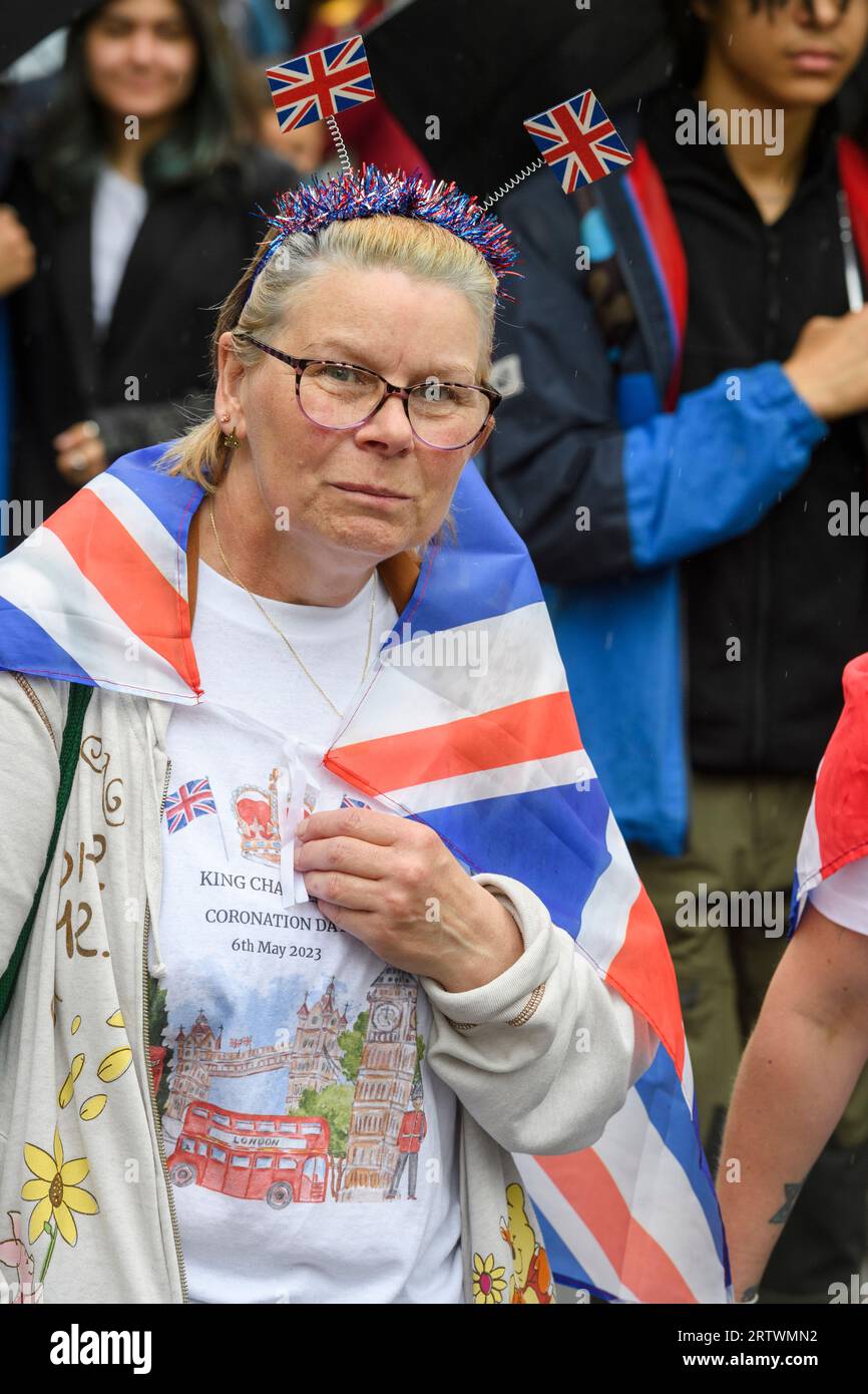 A woman with a Union Jack flag draped around her neck walks down ...
