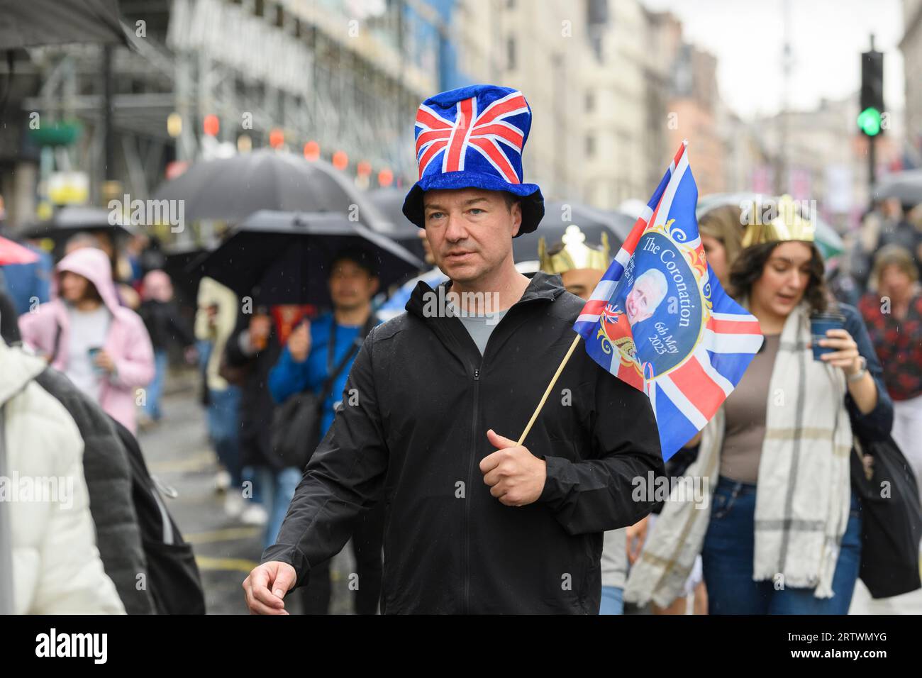 A man wearing a Union Jack hat walks down Piccadilly in the rain, part ...