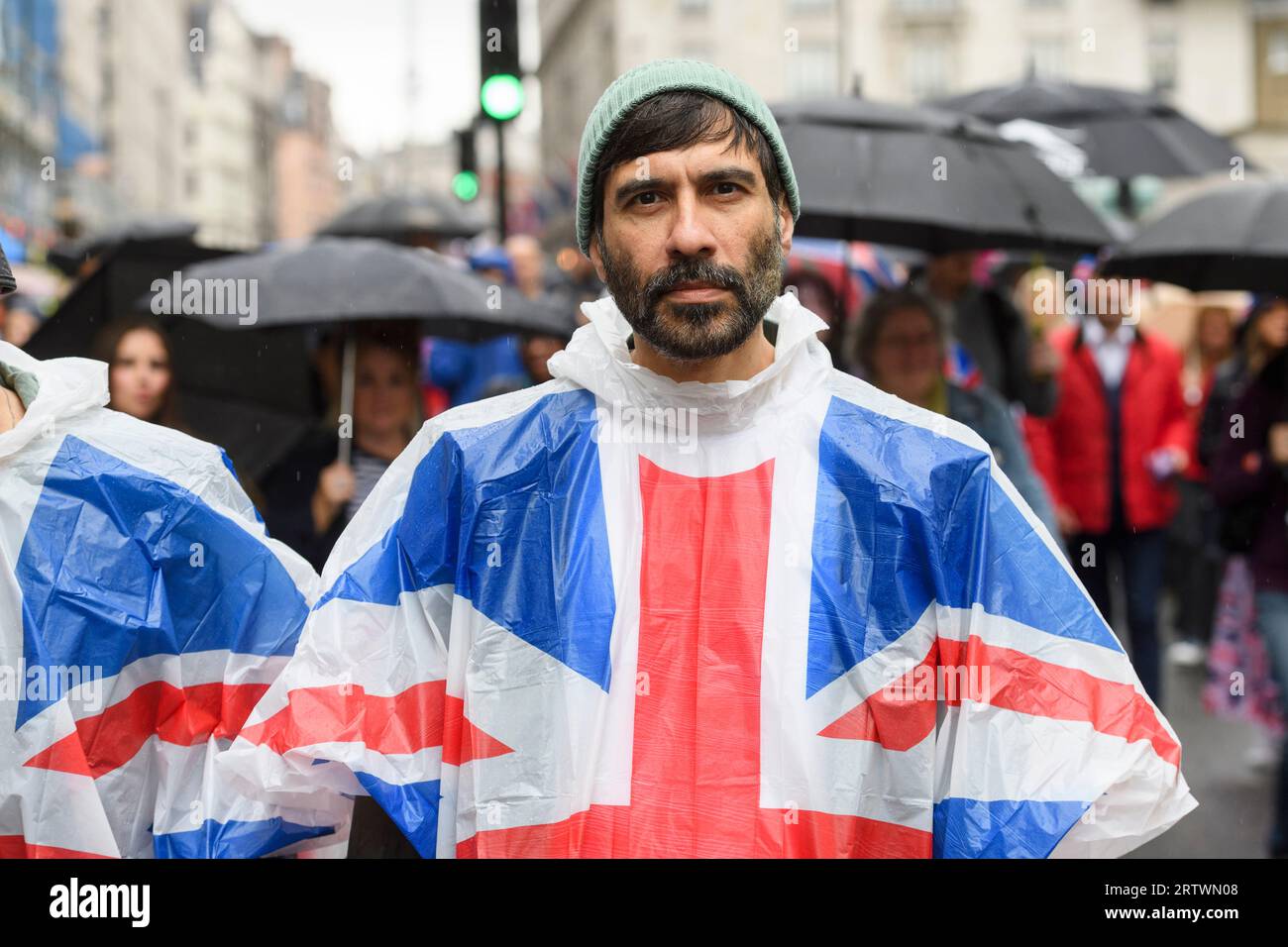 A man wearing Union Jack ponchos walks down Piccadilly in the rain ...