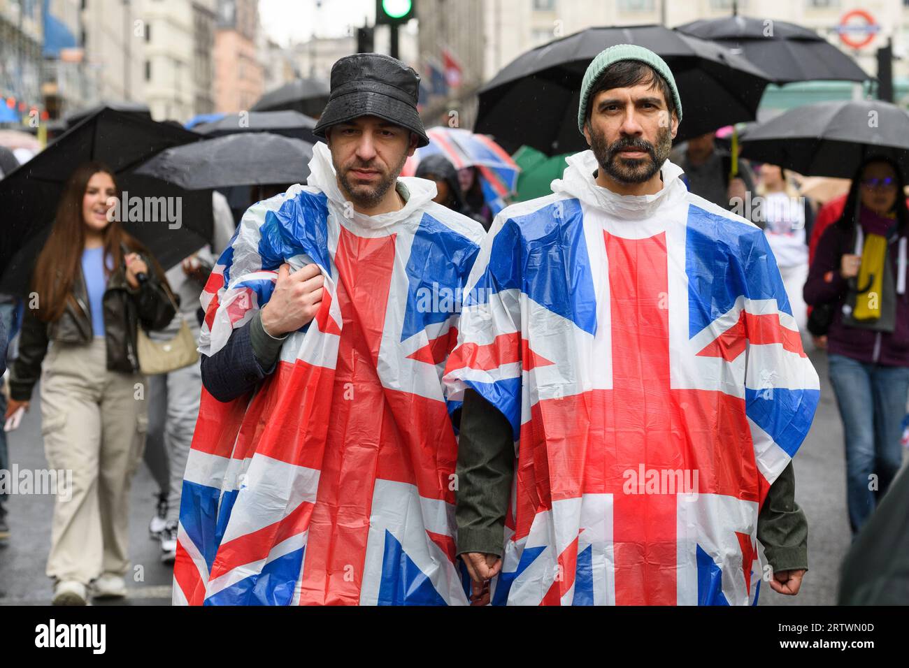 Two men wearing Union Jack ponchos walk down Piccadilly in the rain ...