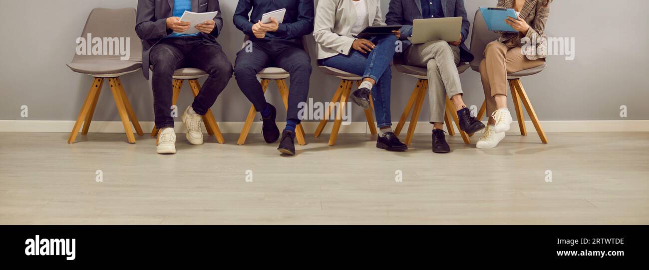 Legs of various people sitting in row in waiting room before interview ...