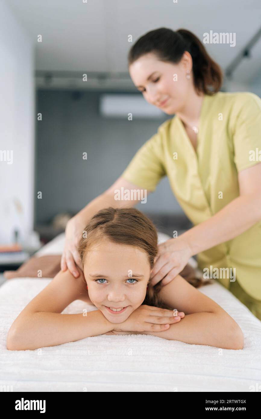 Vertical portrait of happy cute little girl having neck, shoulder and ...
