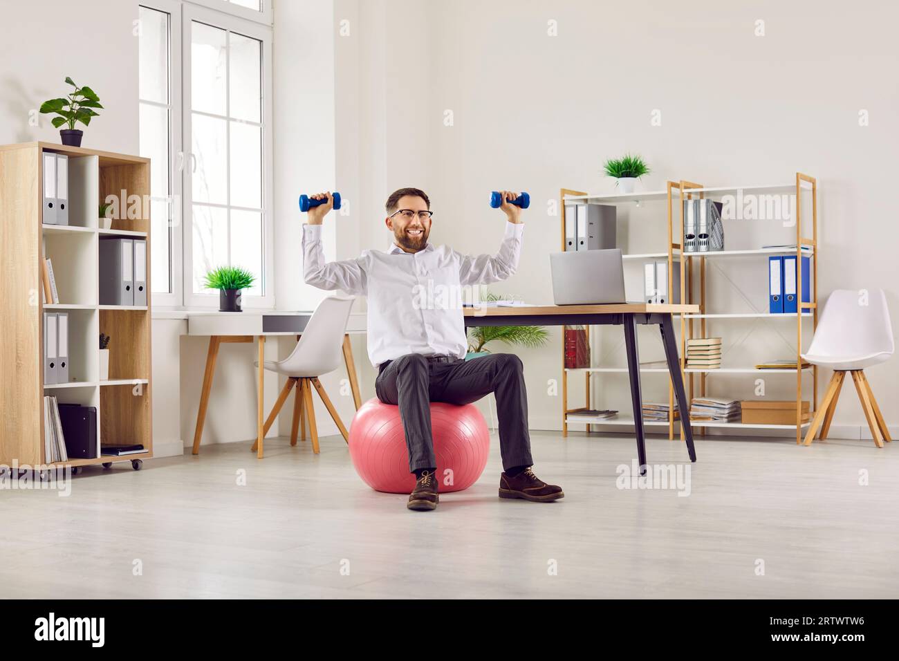 Funny young business man doing sport exercises on fit ball with ...