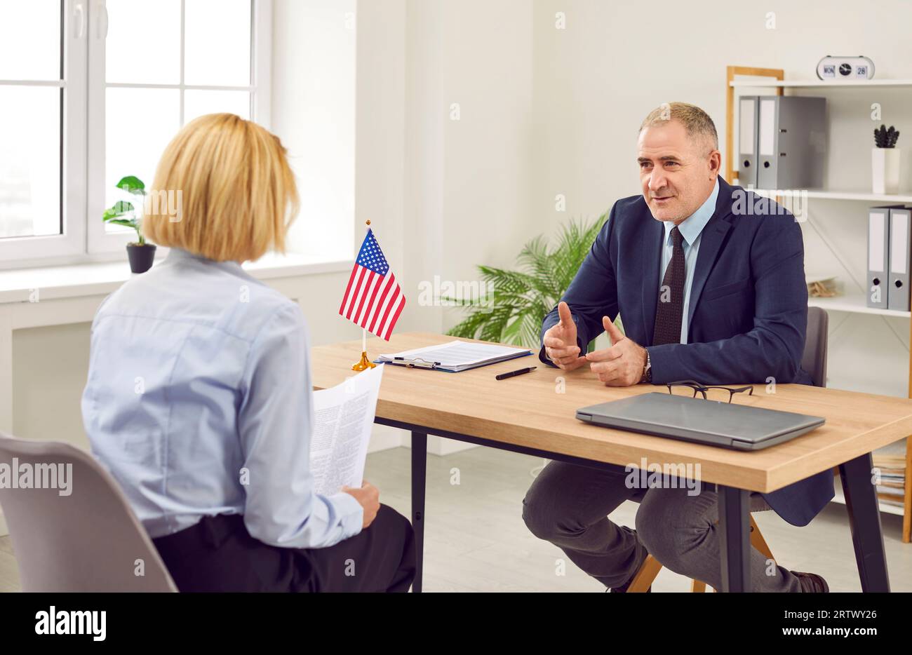 Woman sitting back in office of US public services or embassy and ...